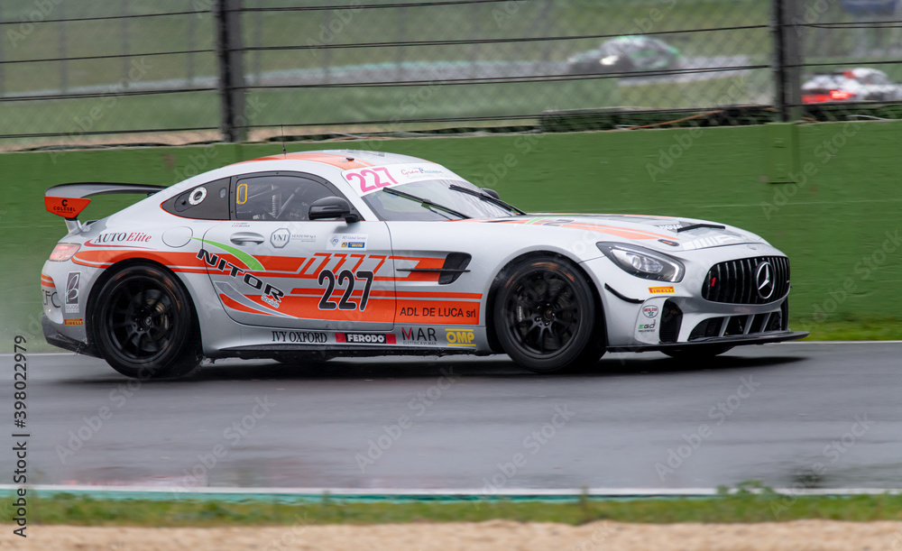Wet race motorsport Mercedes AMG racing car spraying water at curve on ...
