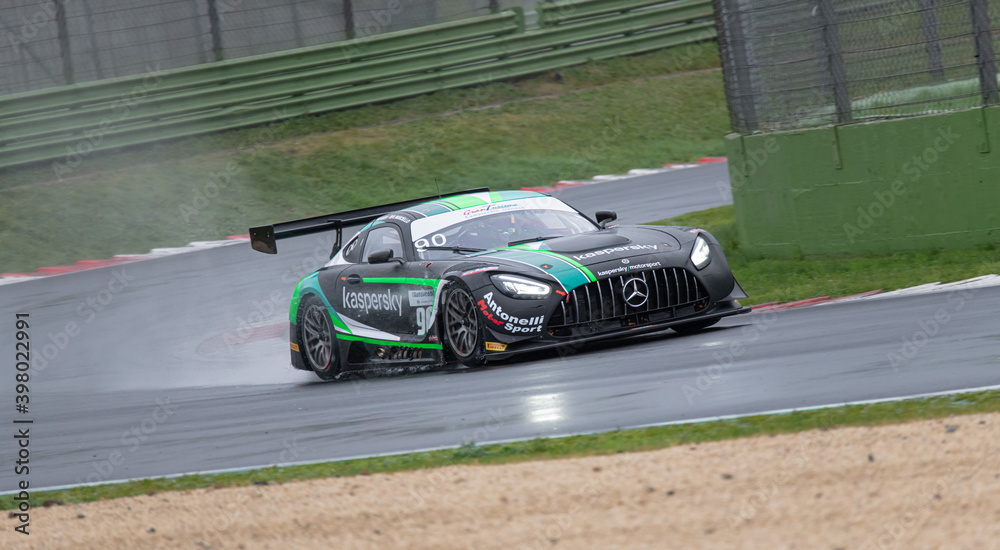 Wet race motorsport Mercedes AMG racing car spraying water at curve on ...