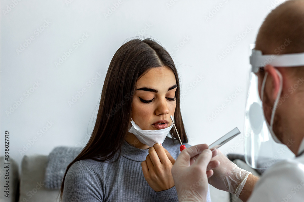 Photo of a professional lab technician in a face shield inserting the ...