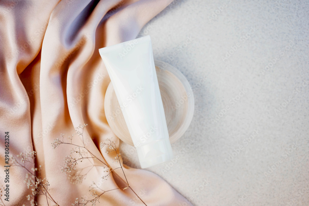 White cosmetic tube on a wooden podium on a silk draped fabric ...