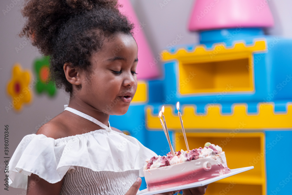 Africa American children hold on celebrating her birthday cake and blow ...