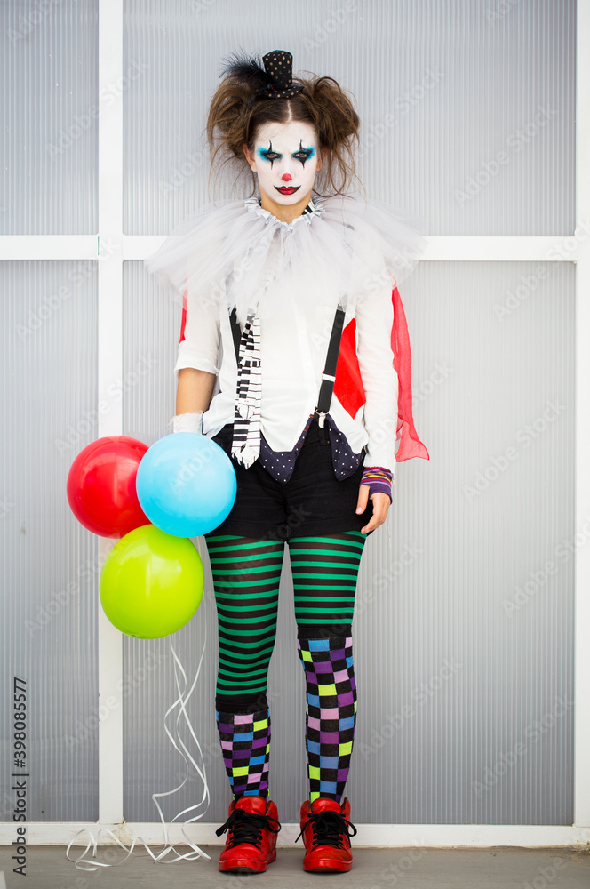 A standing woman dressed up as a terrorific and devilish clown in many ...