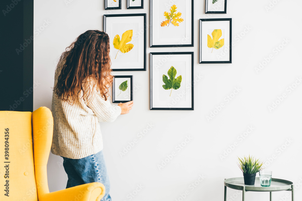 Woman hanging picture frame on wall in new house. Home decor ideas for ...