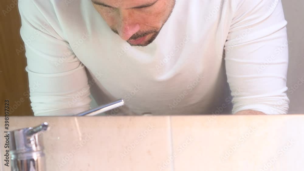 Reflection in a mirror of an attractive man washing his face. Concept ...