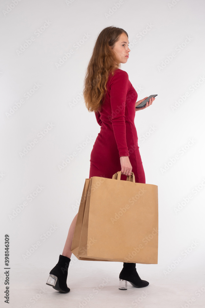 Woman walks with a paper bag. Girl in a red dress with a phone. Young ...