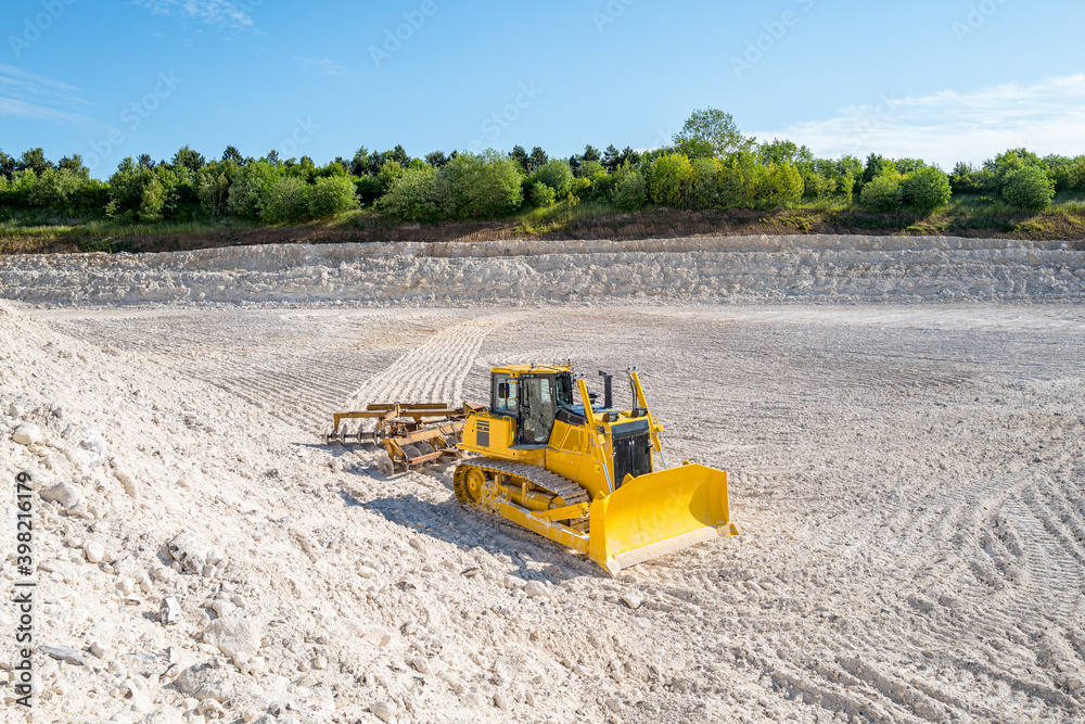 Yellow bulldozer flattening the ground in the limestone quarry. Faxe ...