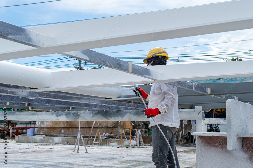 The painter is working to fireproof paint on steel structure with spray ...