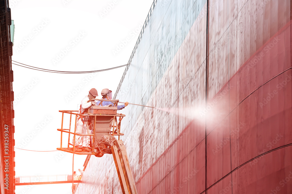 Worker Cleaning ship by water jet cleans at floating dry dock in ...