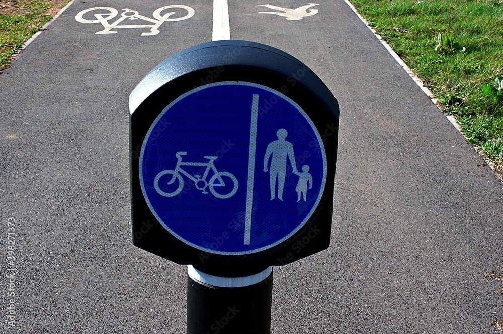 Circular shared cycling and walking sign with white road markings of ...