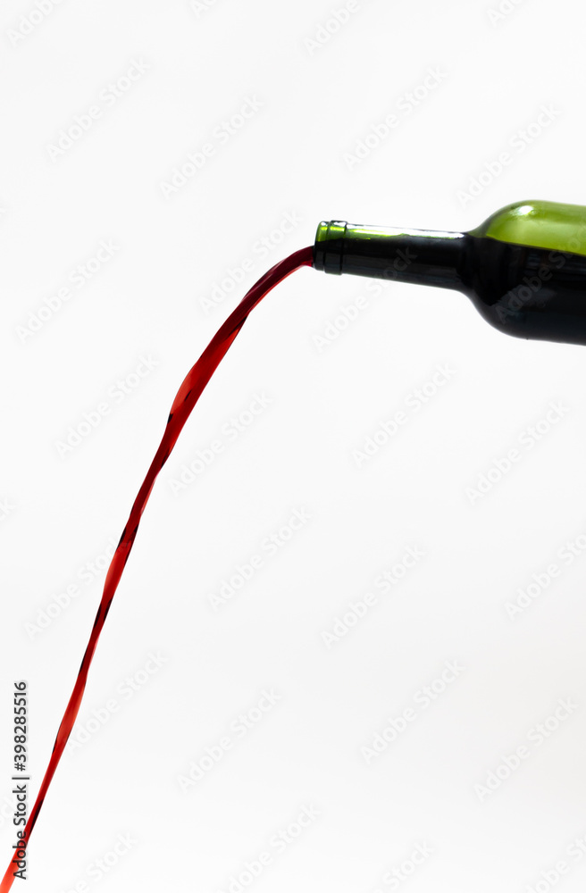 Red wine pouring out of a bottle with long stream on white background ...