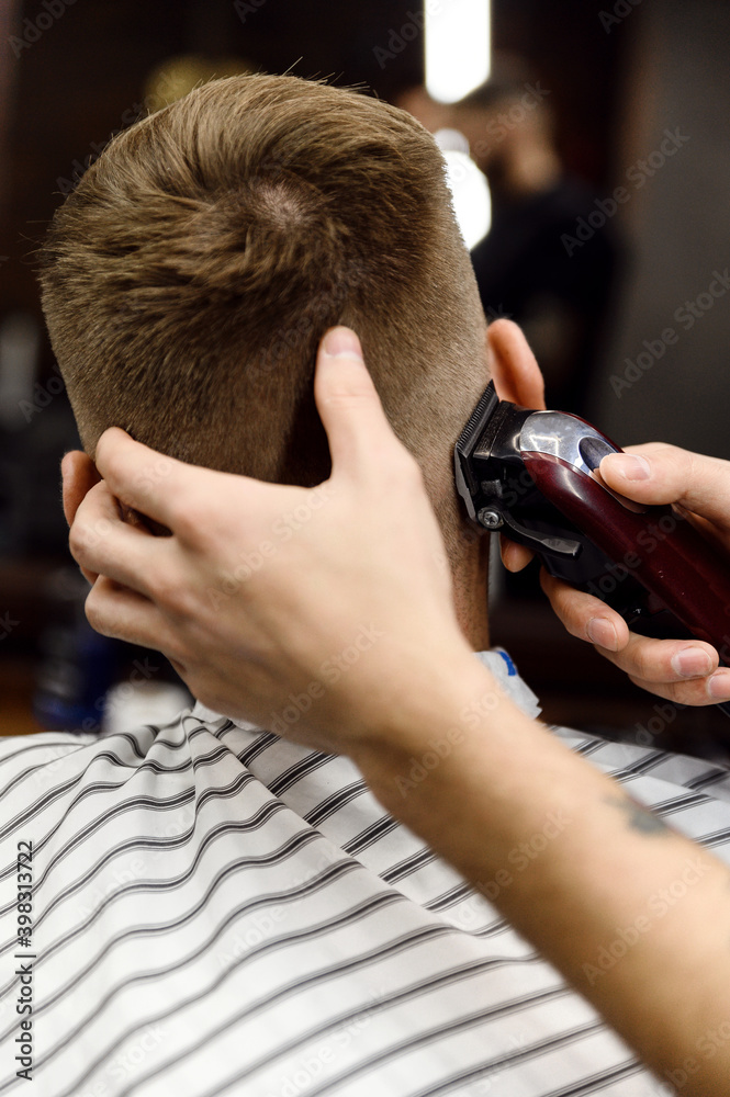 barber cuts a client in a stylish barbershop. men's haircut with a ...