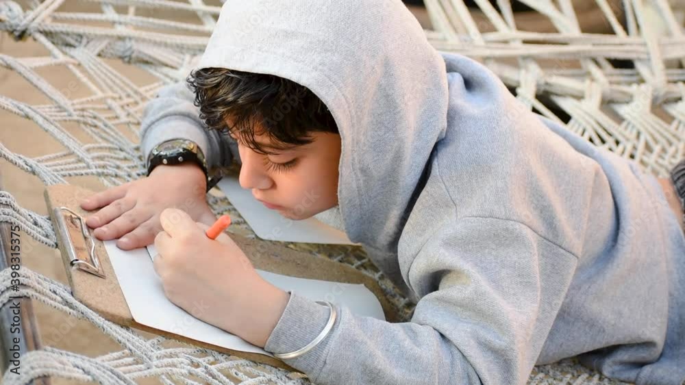 Portrait of Indian school kid drawing, sketching on page with pensile ...