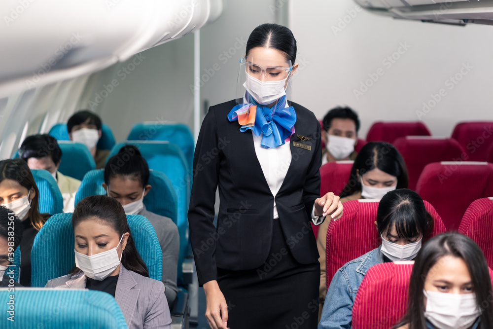 Beautiful Asian flight attendant wearing face mask, providing services ...