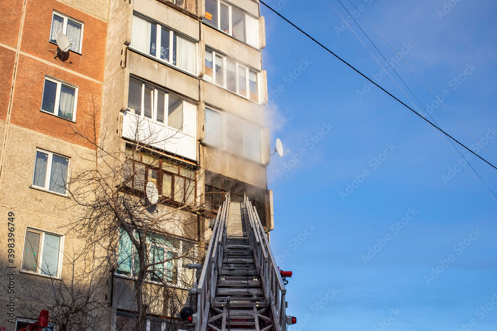 a firefighter extinguishes a balcony, in a high-rise building, from a ...