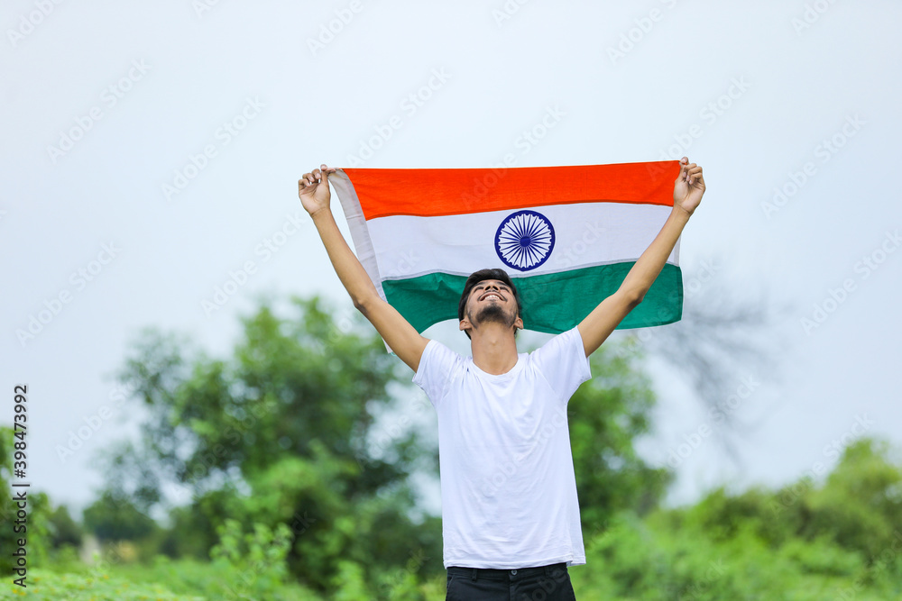 Young indian man waving indian national flag over nature background ...