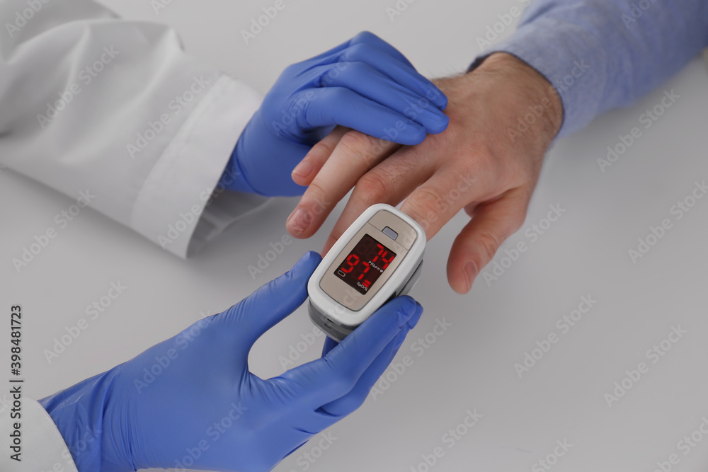 Doctor checking patient's oxygen level with pulse oximeter at light ...