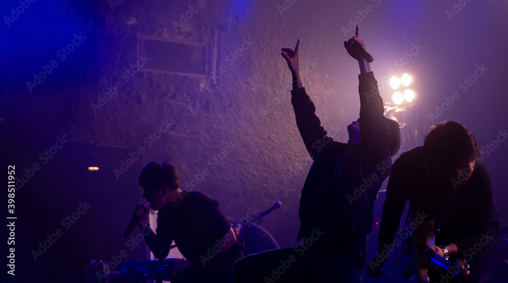Silhouette of Rock band with vocalist show hands raised up performing ...