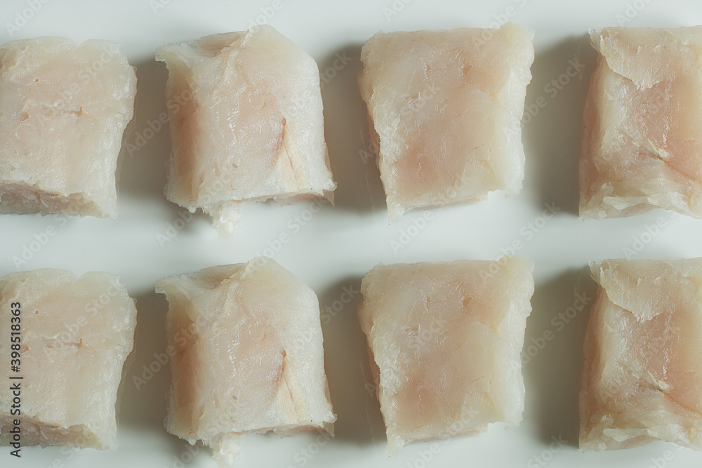 Pieces of raw hake in line on white ceramic texture background. Stock ...