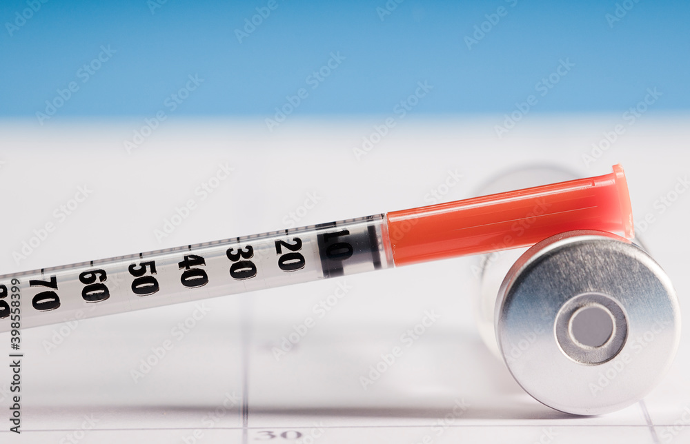 syringe with orange cannula and transparent vial with aluminum closure ...