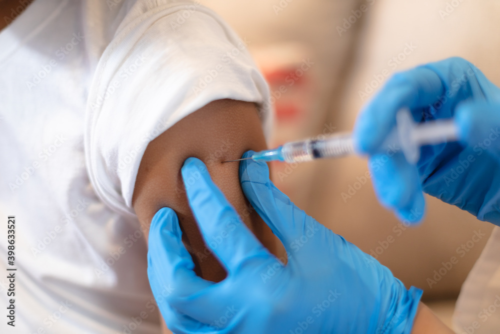 Mixed race girl being given flue vaccine by female doctor wearing ...