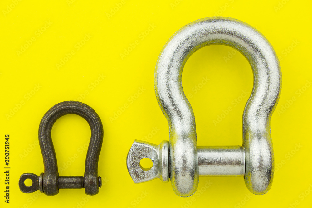 Large and small metal rigging shackles on yellow background ...