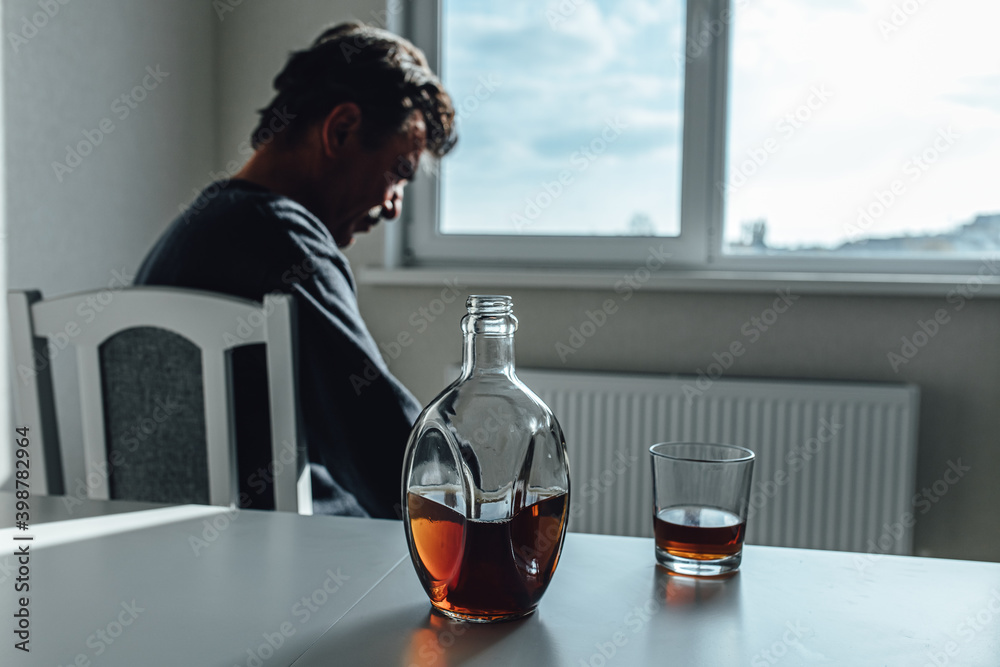 Depressed alcohol addict sitting near window..Side view of sad mature ...