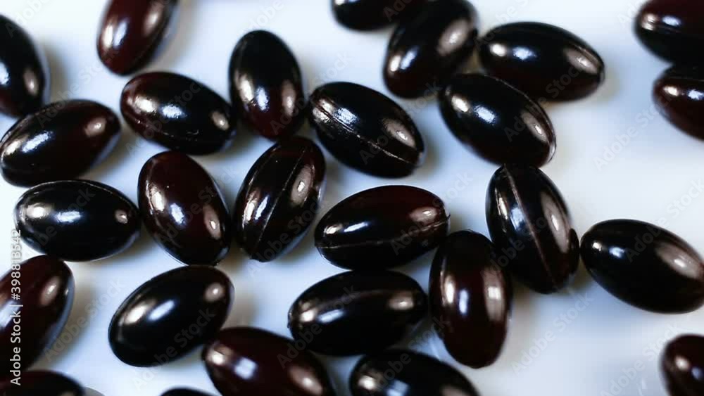 Black oval spindle-shaped gelatin capsules for chewing move in the ...