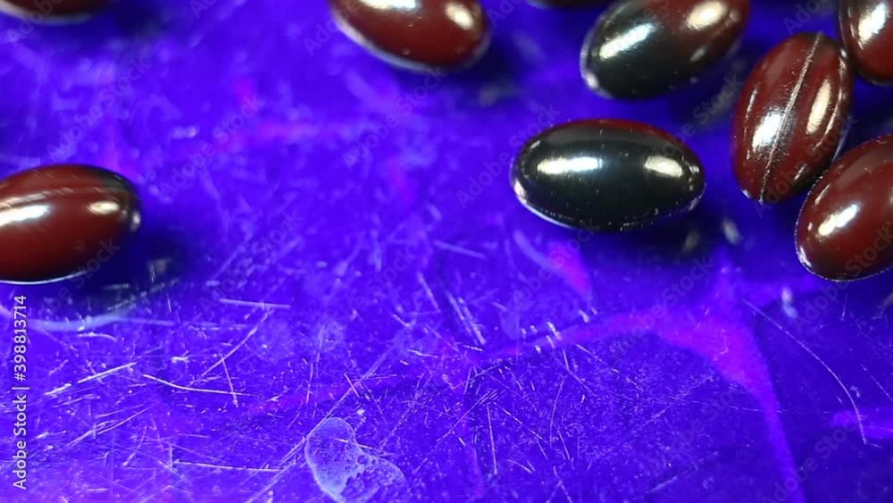 Maroon and black oval spindle-shaped capsules in a gel shiny shell ...