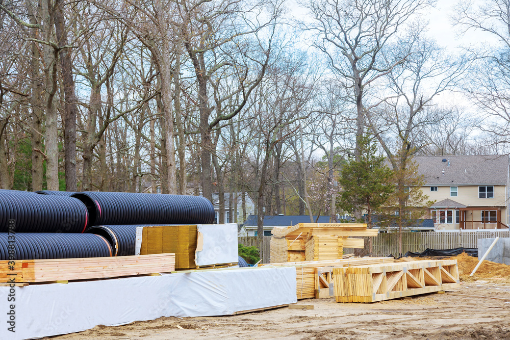 Plastic PVC pipes stacked at wooden building materials stack of boards ...