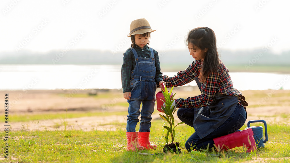 Asian family mom and kid daughter plant sapling tree outdoors in nature ...