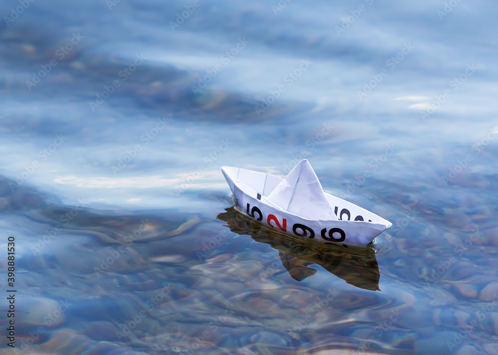 Paper boat made from the calendar sheet floating on the water surface ...