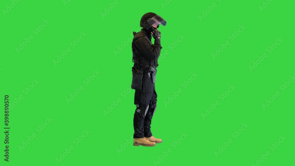 Riot policeman in full uniform talking on a radio on a Green Screen ...