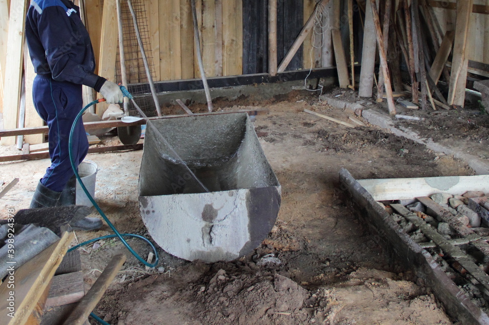 One worker man mix cement mortar with a water in a large basin against ...