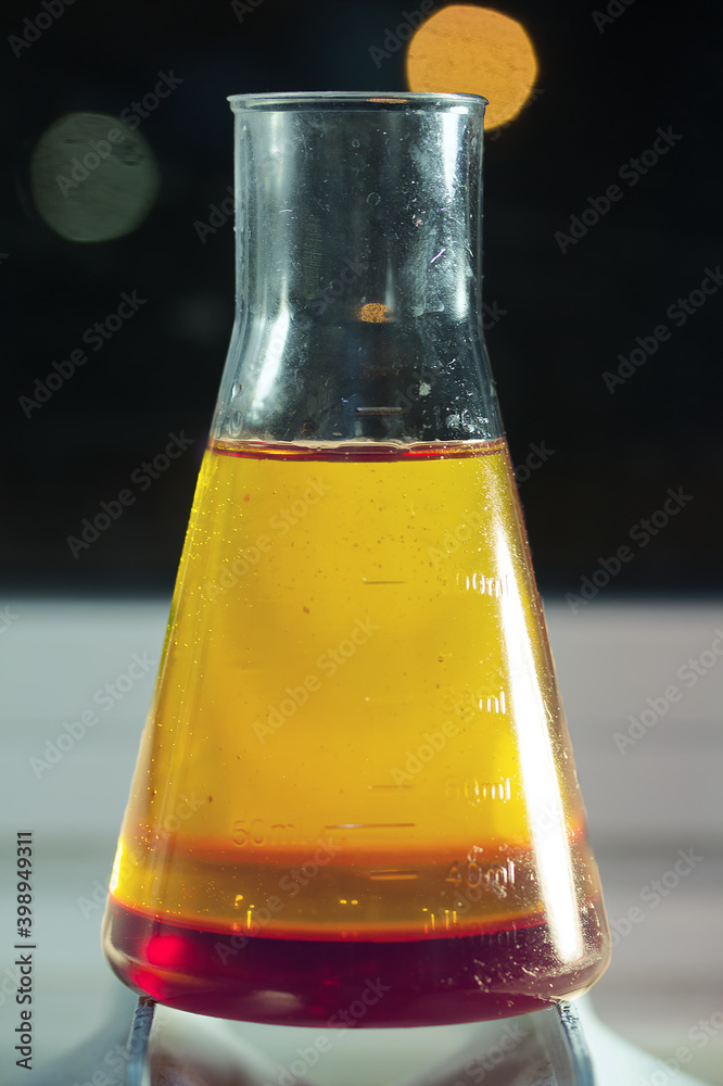Matraz sobre superficie blanca. Contiene dos líquidos: el inferior es ...