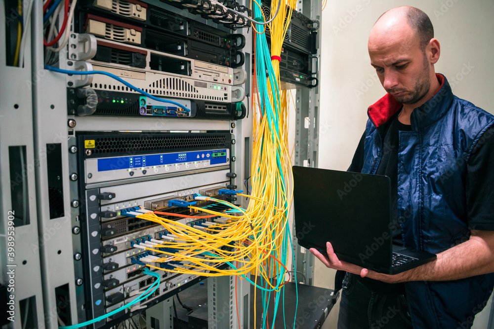 The system administrator with a laptop is in the server room. A man ...