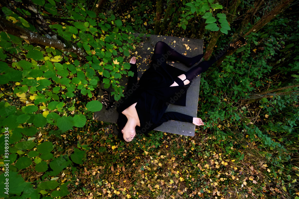 sexy young brunette woman, lying dead in a black dress on square table ...