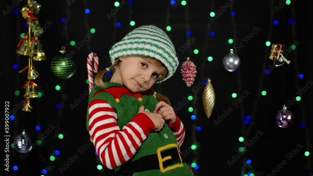 Shy shamed child girl in Christmas elf Santa helper costume posing and ...