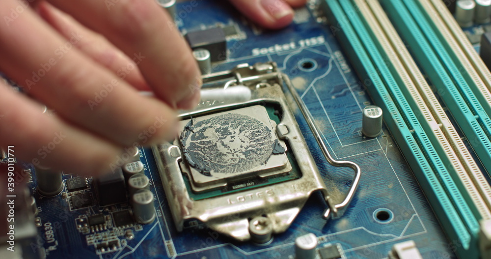 The repairman cleans the CPU of the laptop from the old thermal grease ...