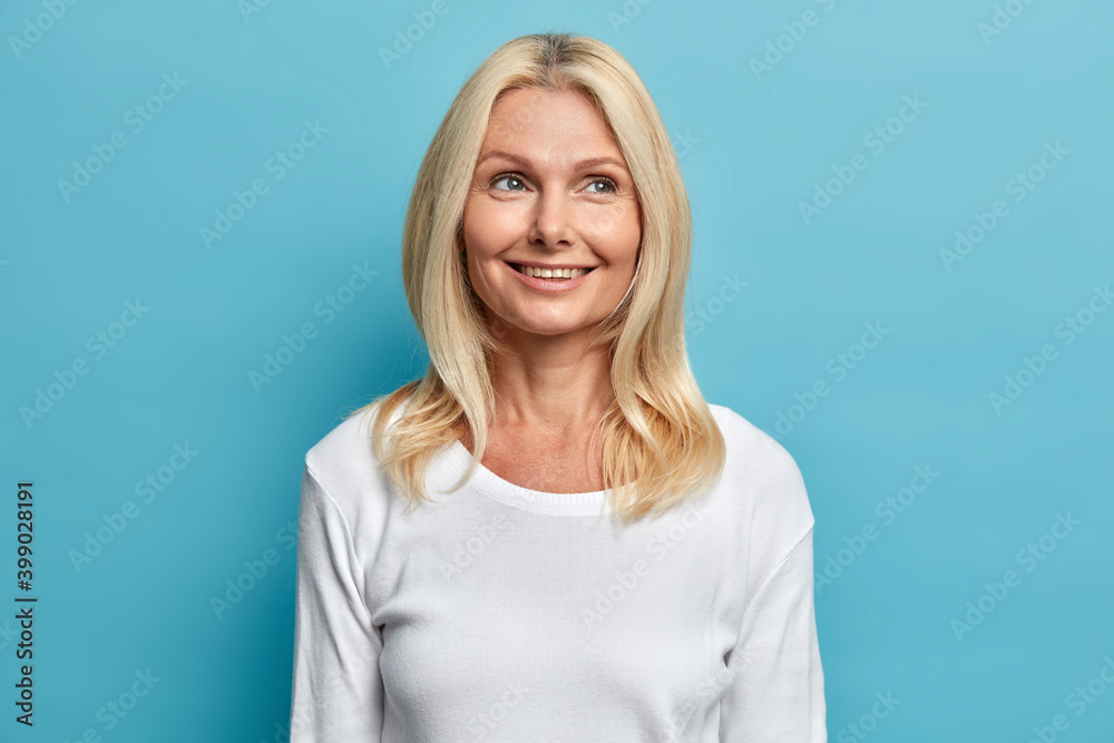 Portrait of beautiful dreamy blonde middle aged woman with pleased face ...