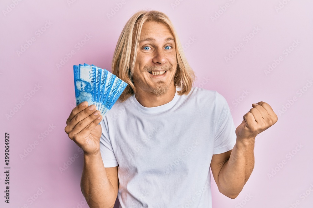 Caucasian young man with long hair holding 10000 chilean pesos ...