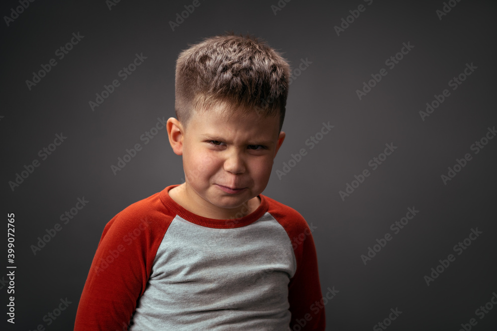 Angry boy frowning, showing with his face dislike isolated on grey ...