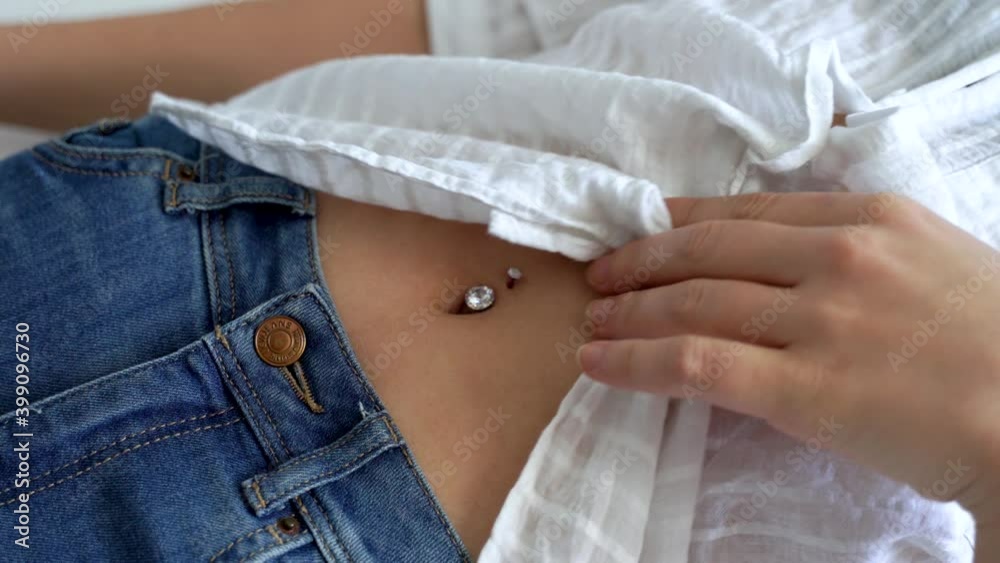 Young woman is showing her belly button or navel piercing isolated on ...