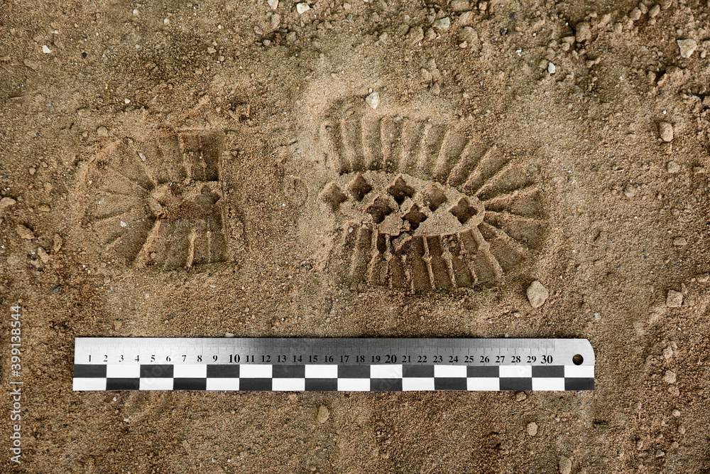 Ruler near footprint on sand, top view. Crime scene investigation and ...