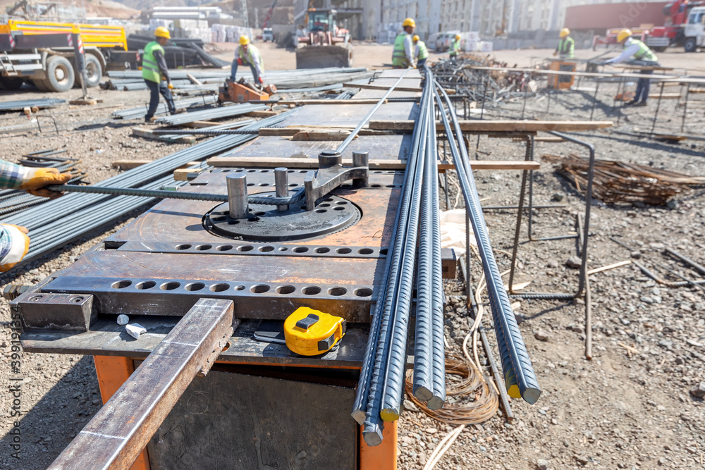 The construction worker is bending rebars. Rebar (rod, reinforcing bar ...