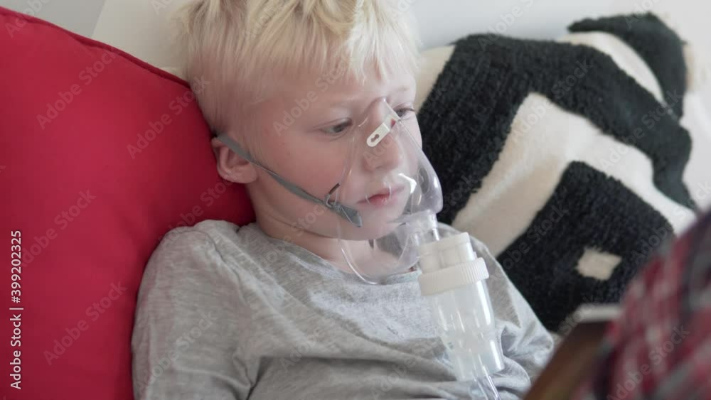 A handsome blonde boy treats at home pneumonia with the help of a ...