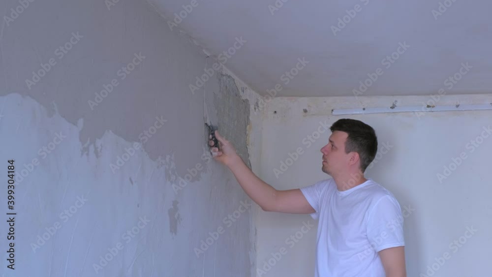 Plasterer man spackling wall with putty plaster aligning wall with ...