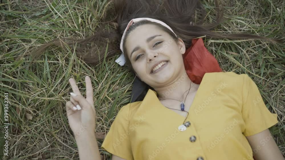 Beautiful young hippie woman lying on green meadow showing peace ...