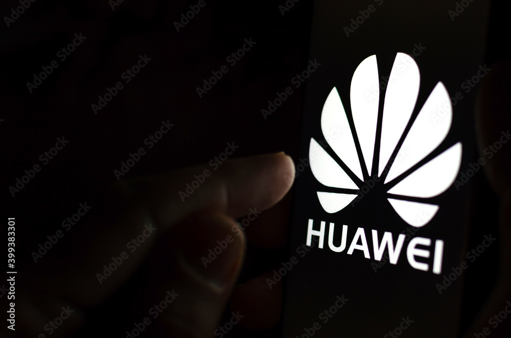 Huawei Logo on a smartphone screen in a dark room and a finger touching ...