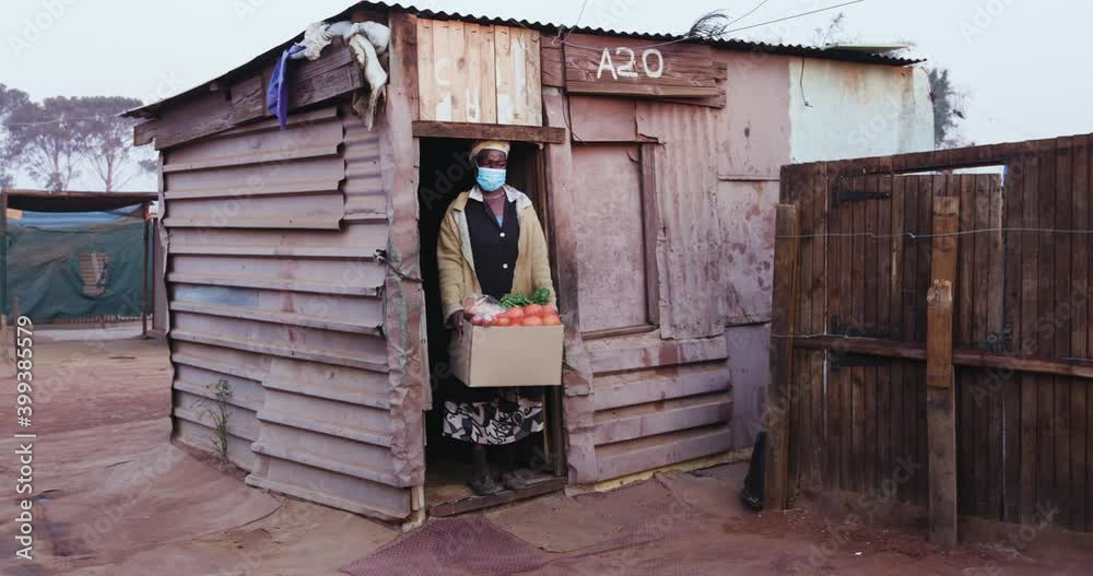 Close-up of an old Black African woman standing in the door way of her ...