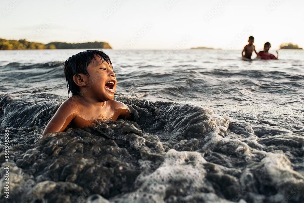 Portrait of a panamanian kid playing alone at the beach with the waves ...